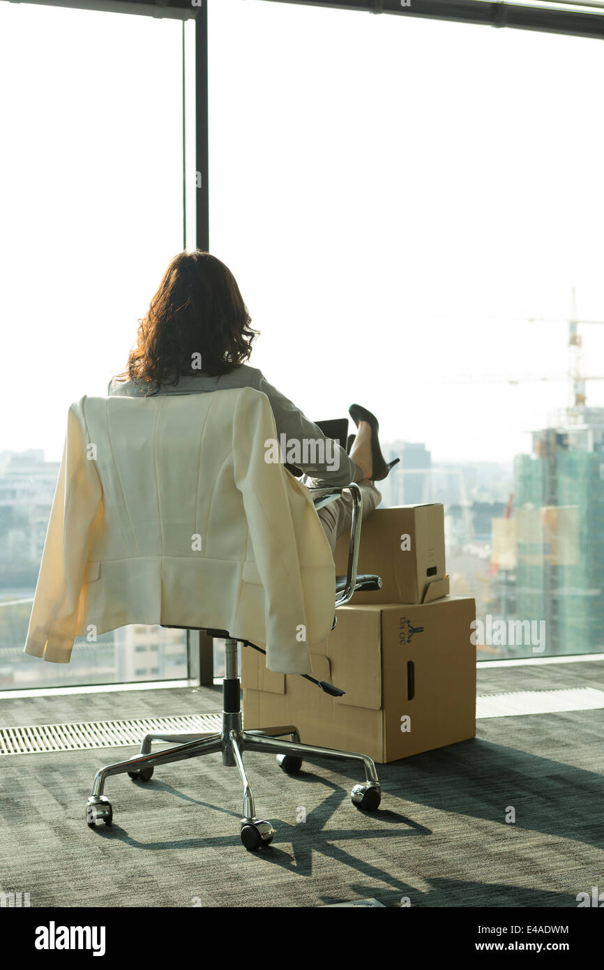 Businesswoman using laptop with feet on cardboard boxes Stock Photo - Alamy