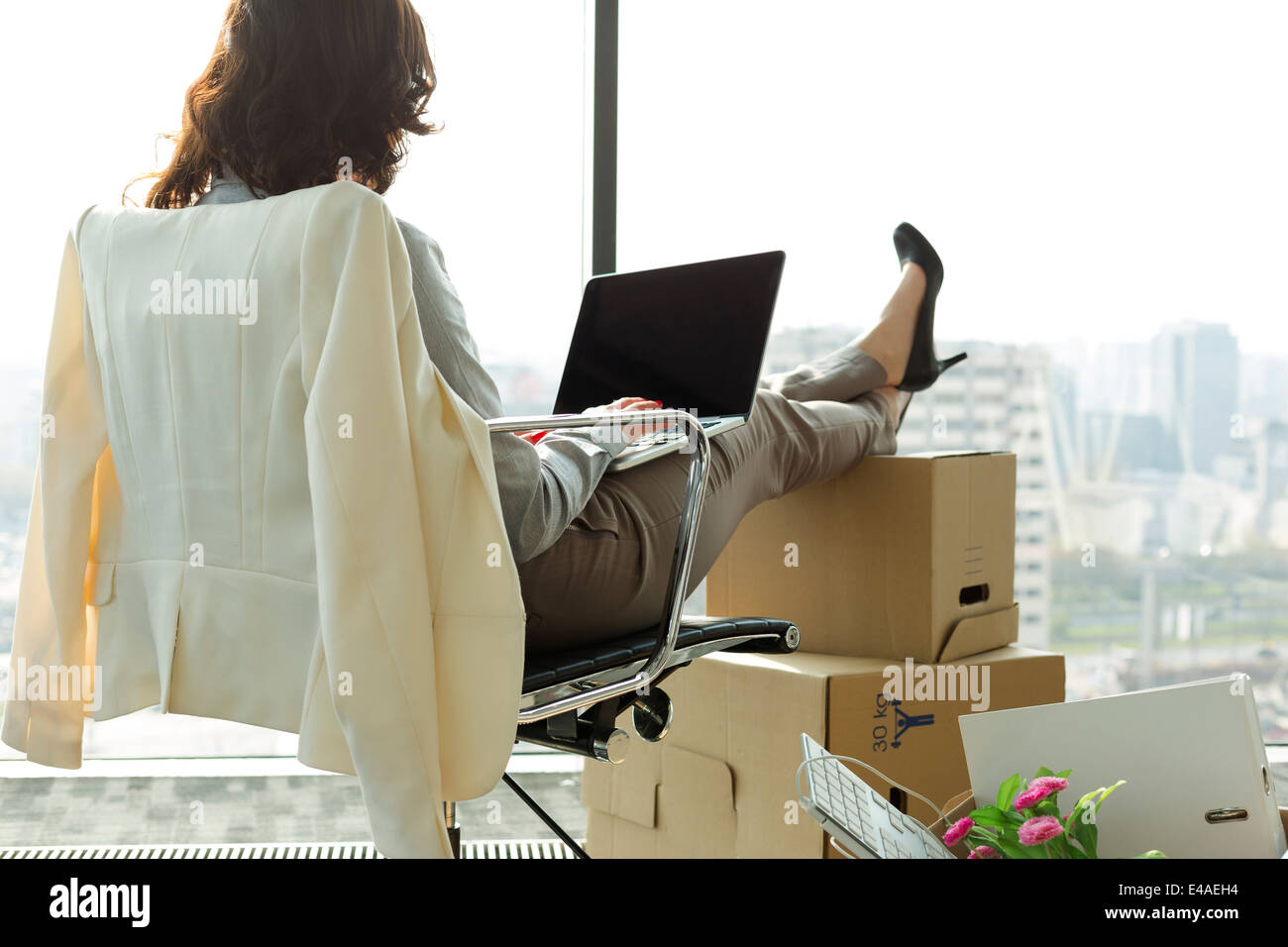 Businesswoman using laptop with feet on cardboard boxes Stock Photo - Alamy