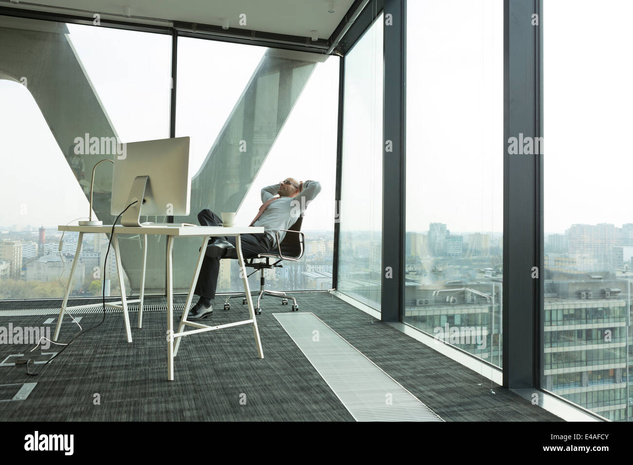 Businessman leaning back in new office Stock Photo - Alamy