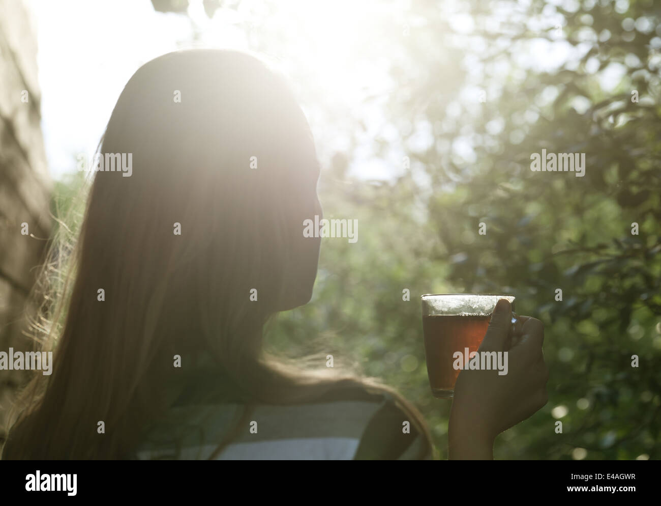 Woman with cup of tea in evening sunlight Stock Photo - Alamy
