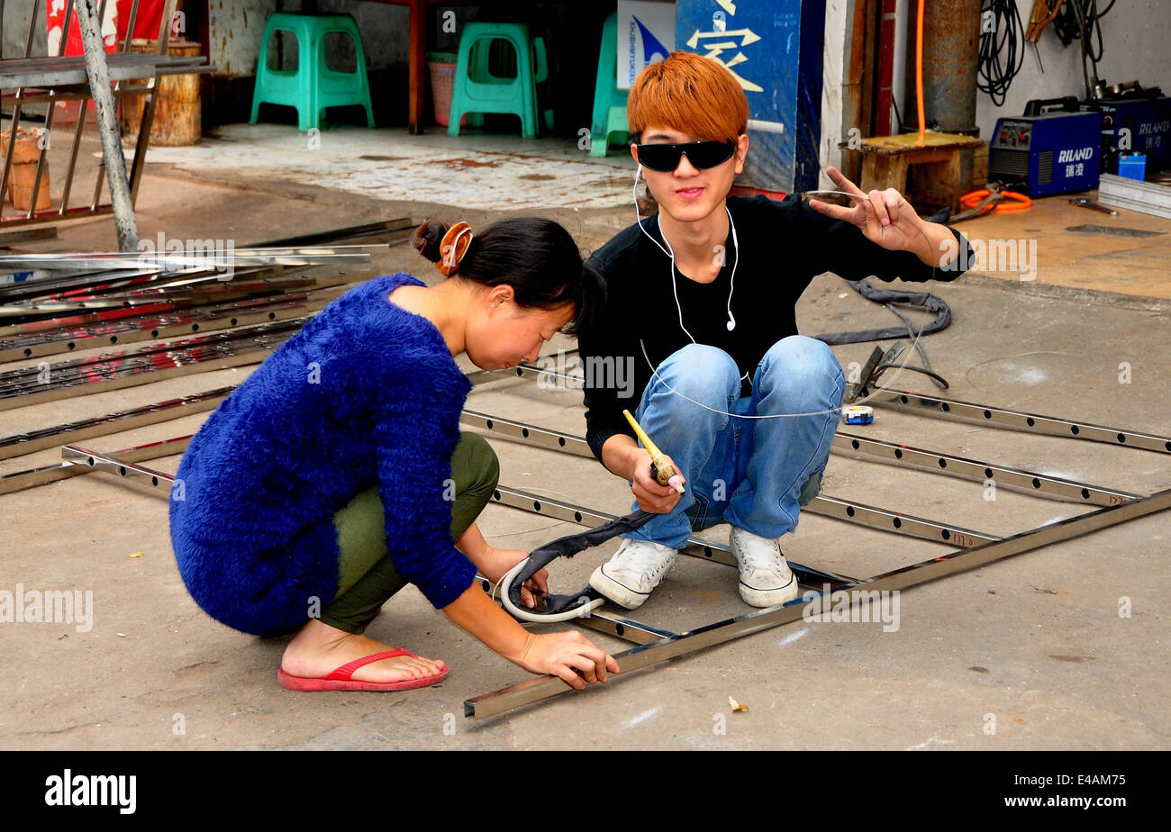 PENGZHOU, CHINA: Two workers welding a steel gate frame in front of ...