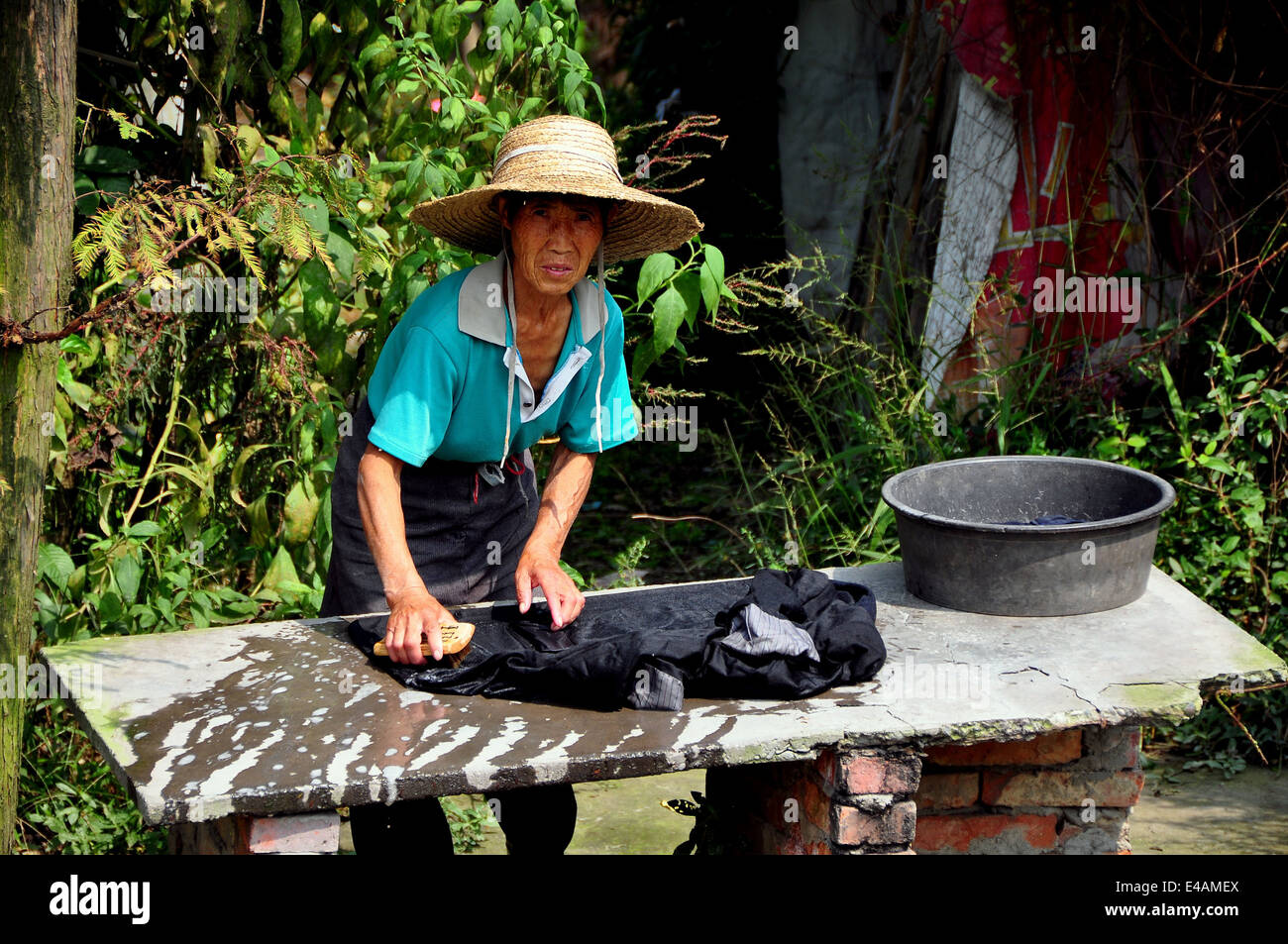 PENGZHOU, CHINA: Woman washing laundry by hand outside on a stone slab ...