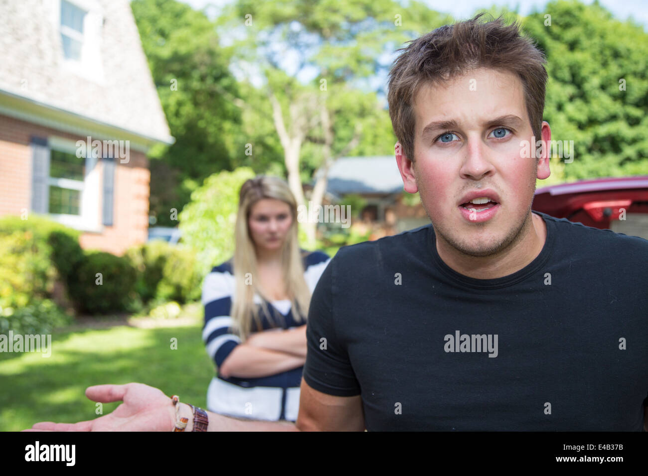 A young man in an argument with his wife, looks to the camera audience ...