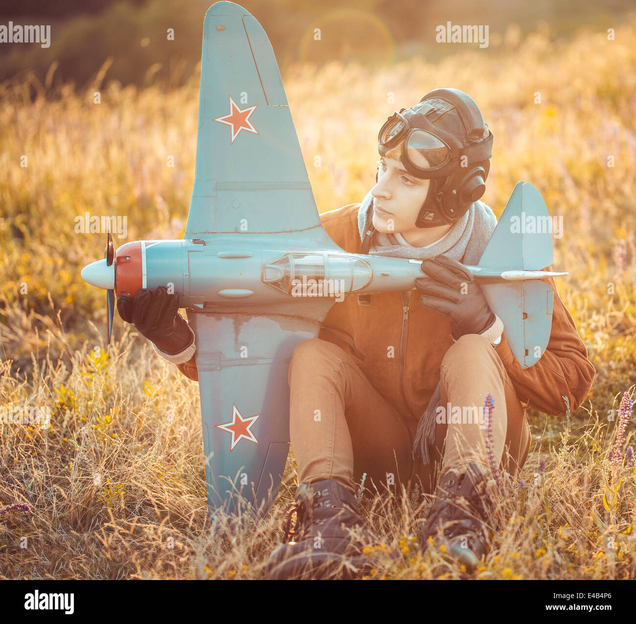 Young guy in vintage clothes pilot with an airplane model outdoors ...
