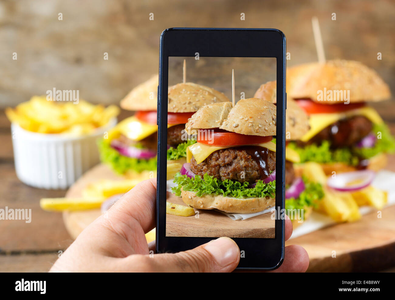 Man shooting with his cell phone camera big and tasy burgers.Selective ...