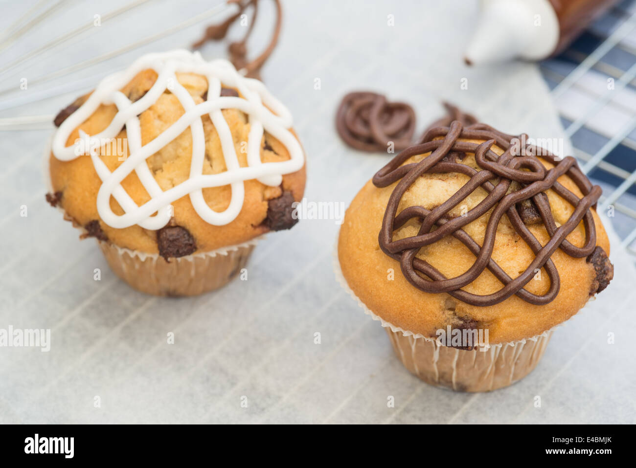 Home made chocolate chip muffins with icing frosting being applied ...