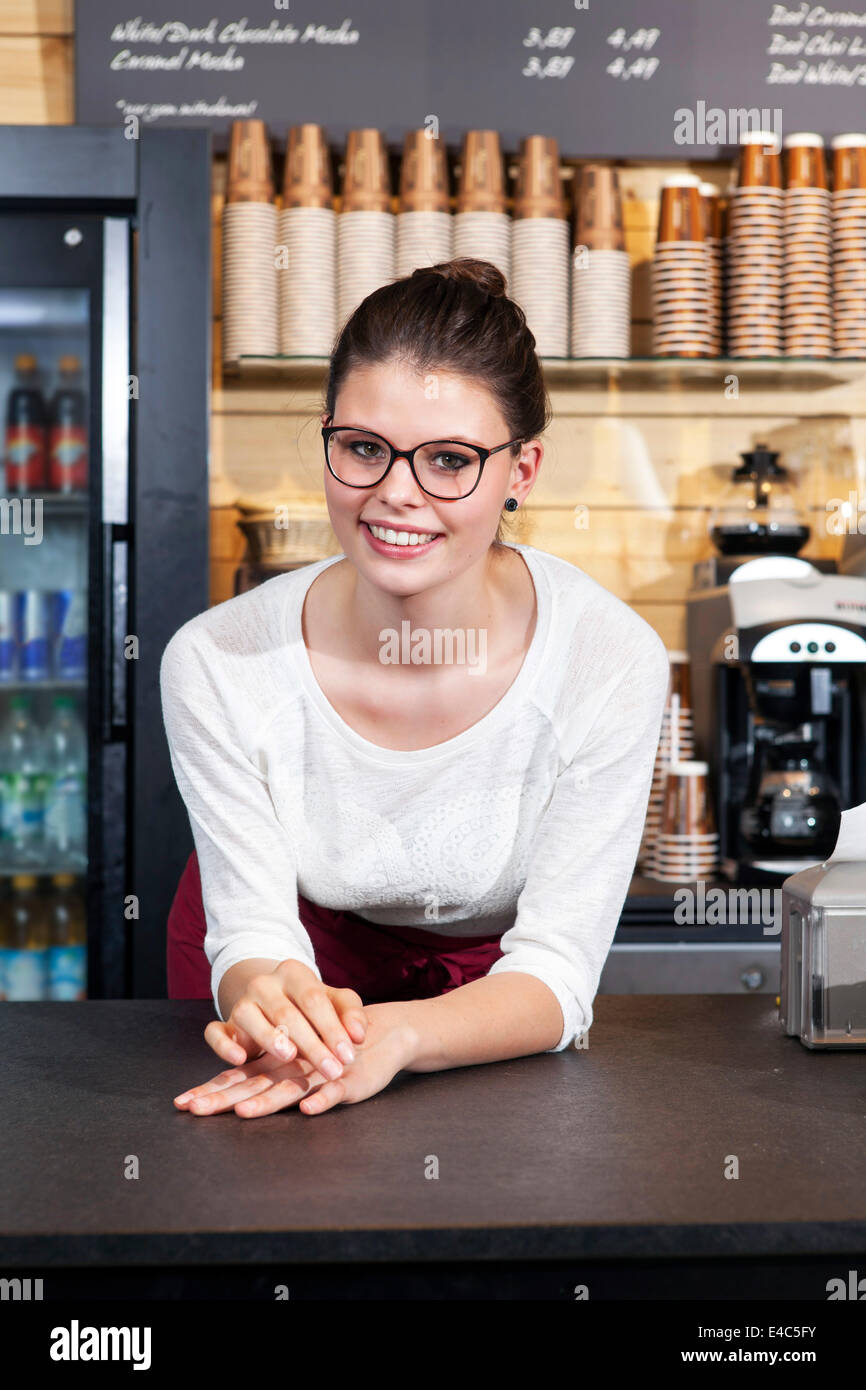 Waitress in coffee shop leaning against counter, portrait Stock Photo ...