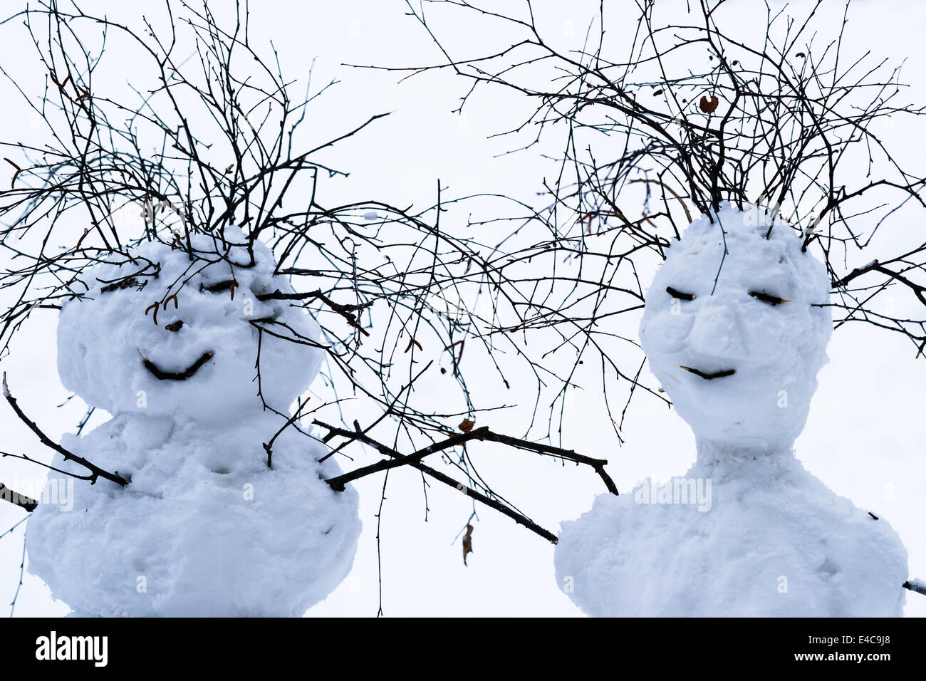 Two smiling snowmen with hair style of dry twigs against white ...