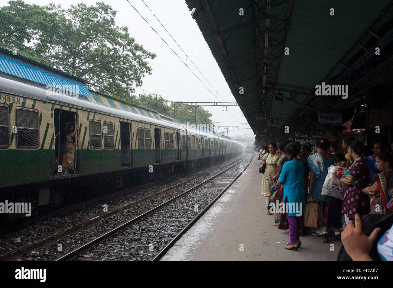 Calcutta, India. 8th July, 2014. Passengers wait to board a train at a ...