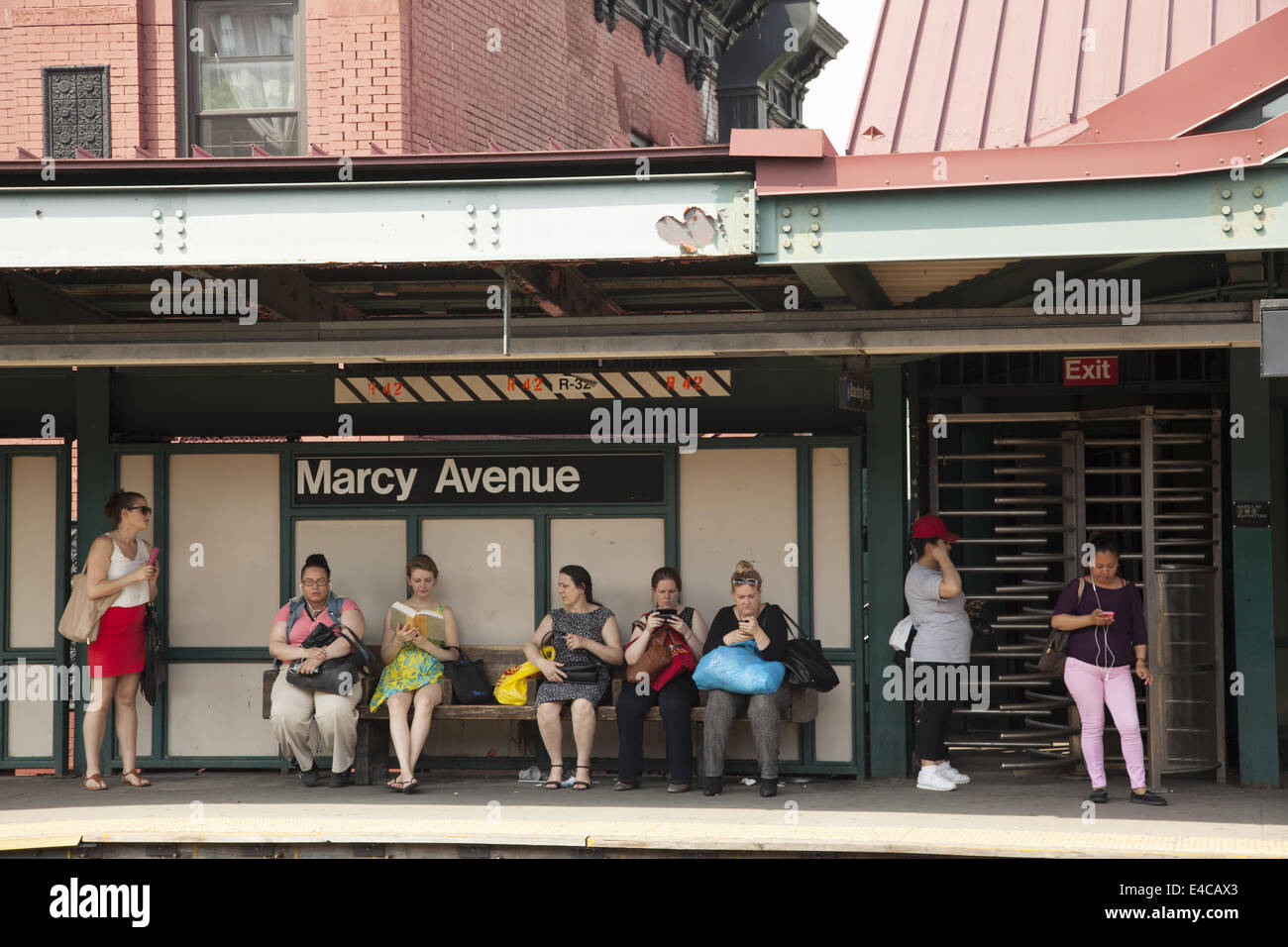 Subway riders wait for an M Train to Manhattan at the Marcy Ave. elevated station in ...