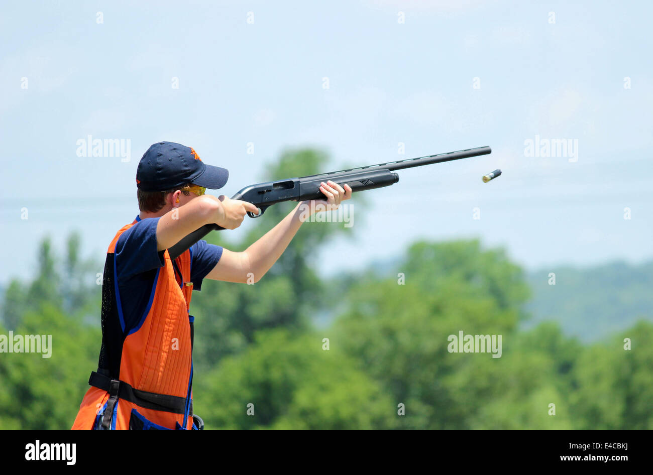 Young man skeet shooting with shotgun throwing shell Stock Photo - Alamy