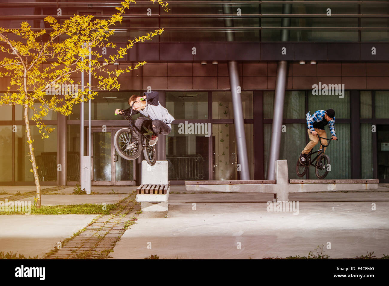 Two BMX bikers performing stunts on the sidewalk Stock Photo - Alamy