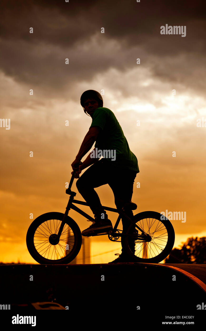 BMX biker with bike standing against sunset Stock Photo - Alamy