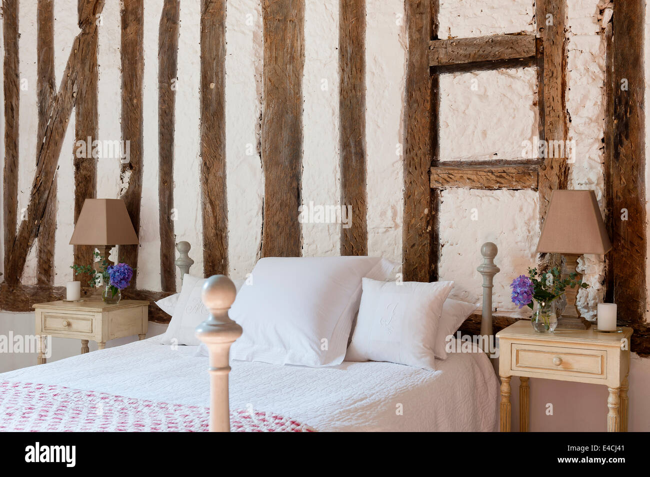 Timber framed wall with rendered infill behind bed with side tables ...