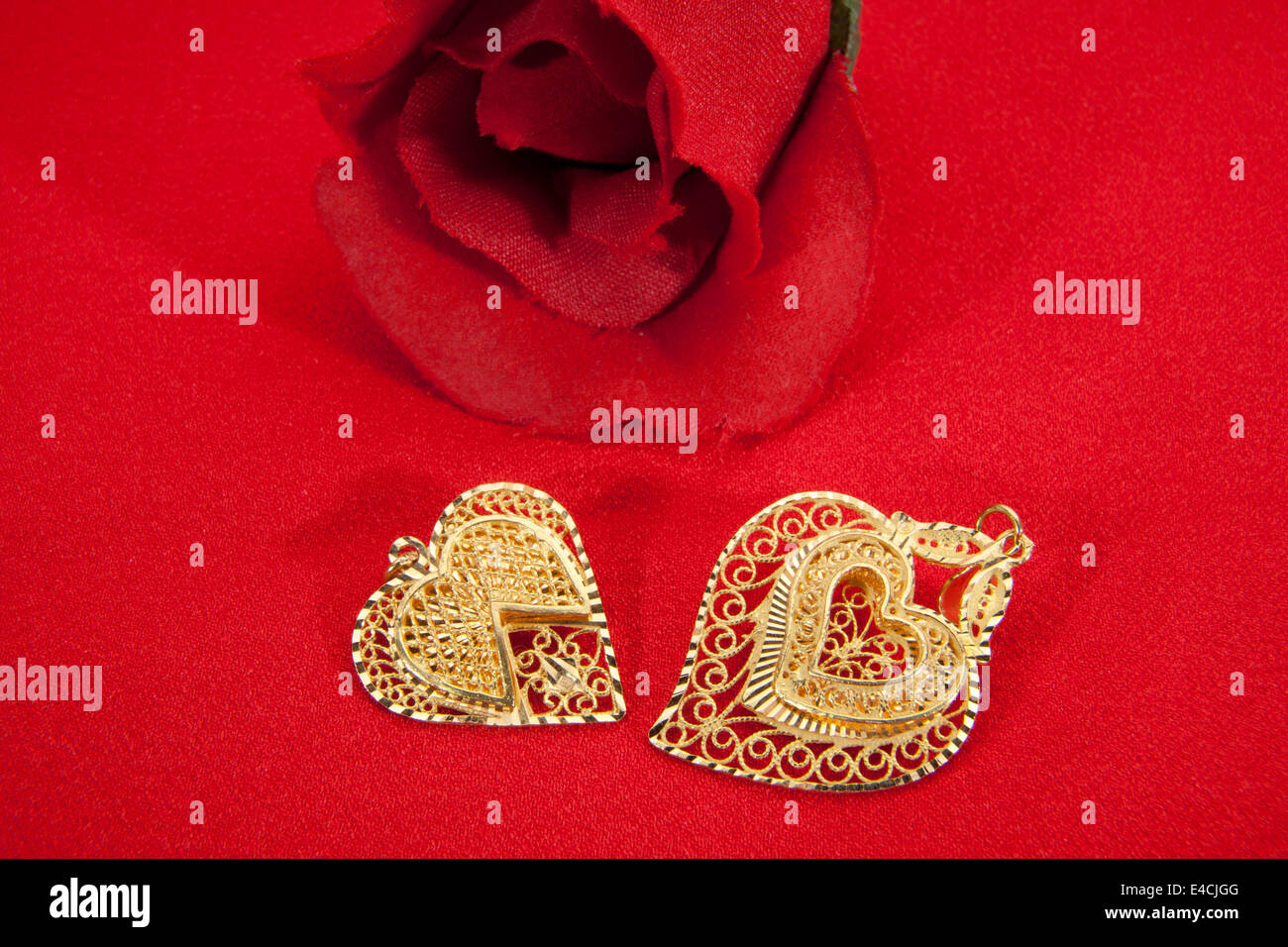 Red rose with gold heart pendants on red silk Stock Photo - Alamy