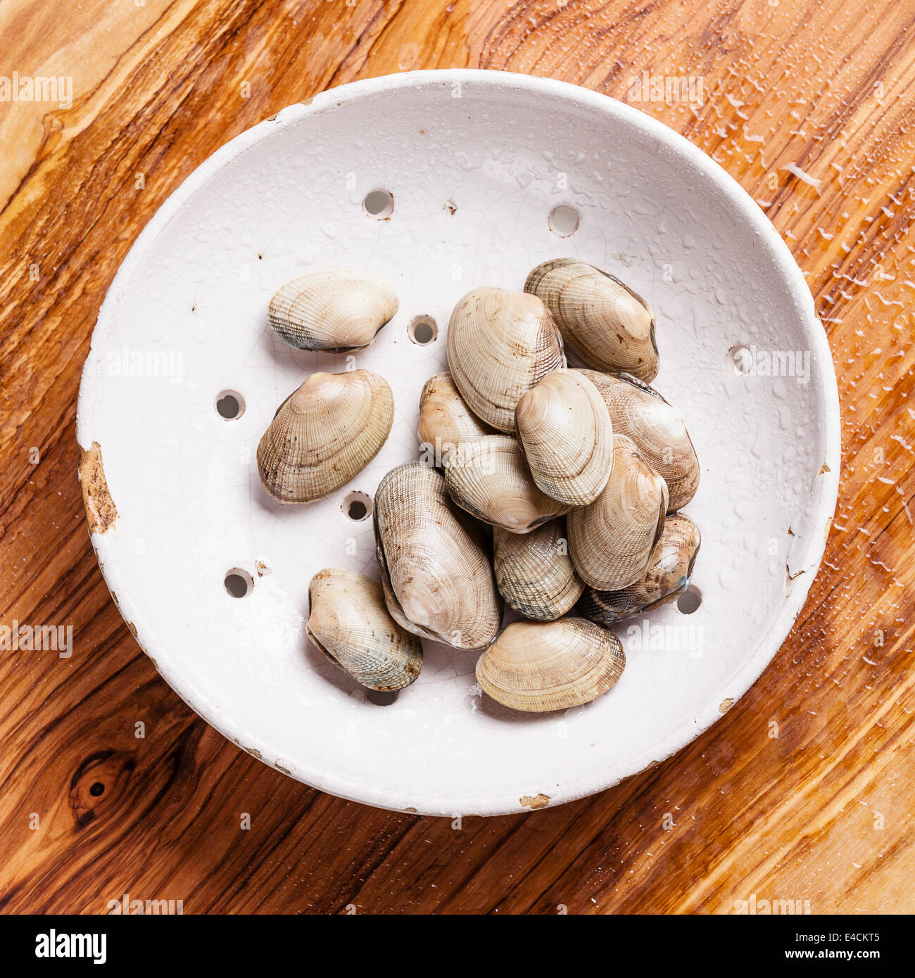 Raw Shells vongole in vintage ceramic colander on olive wood background ...