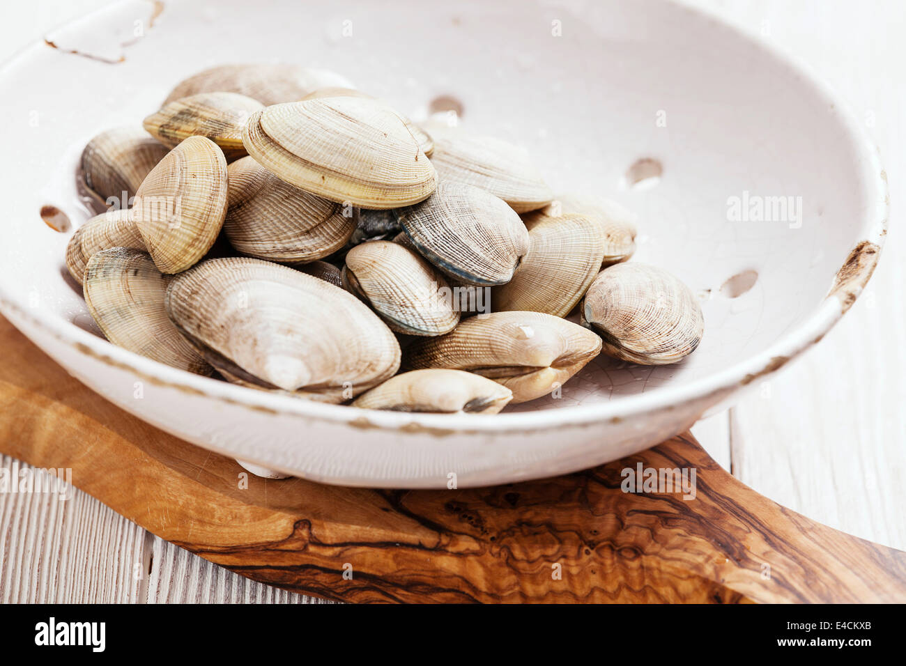 Raw Shells vongole in vintage ceramic colander on white wooden ...