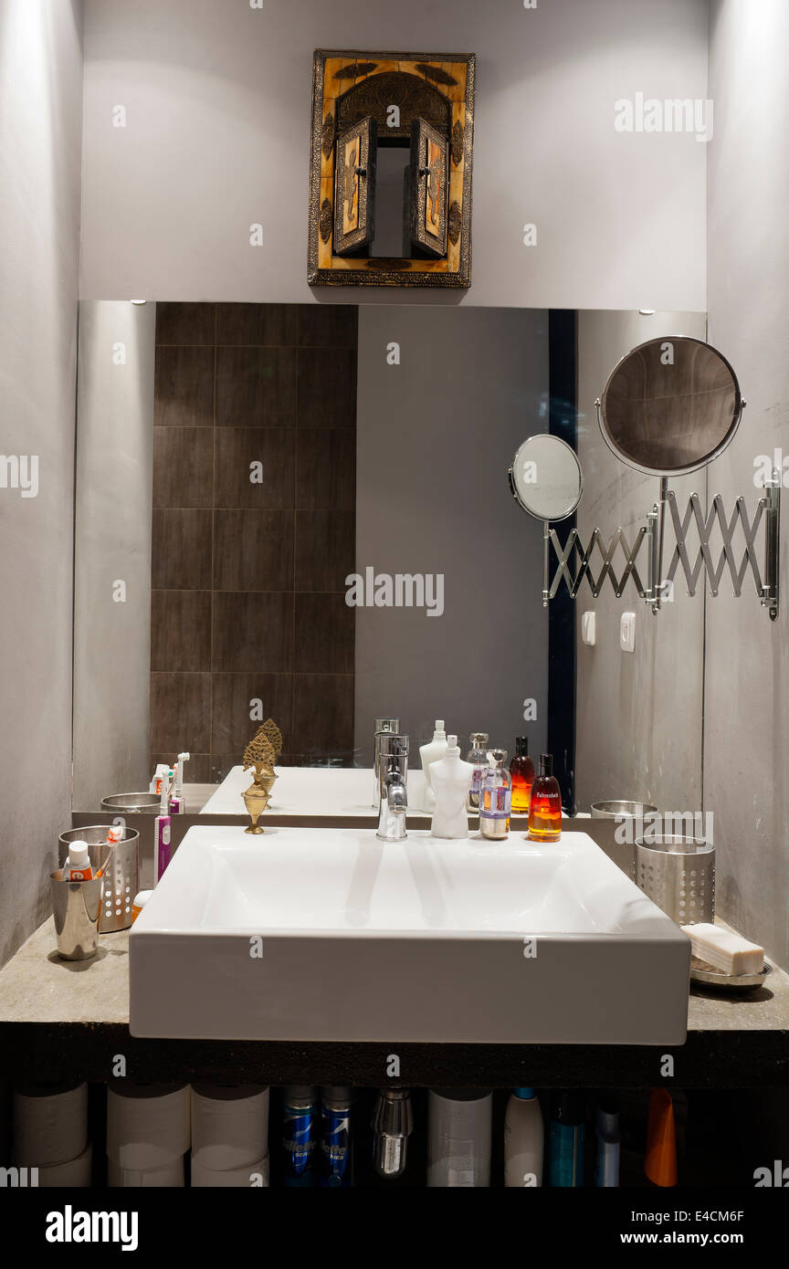 Square basin set into a stone base in bathroom alcove with large mirror ...