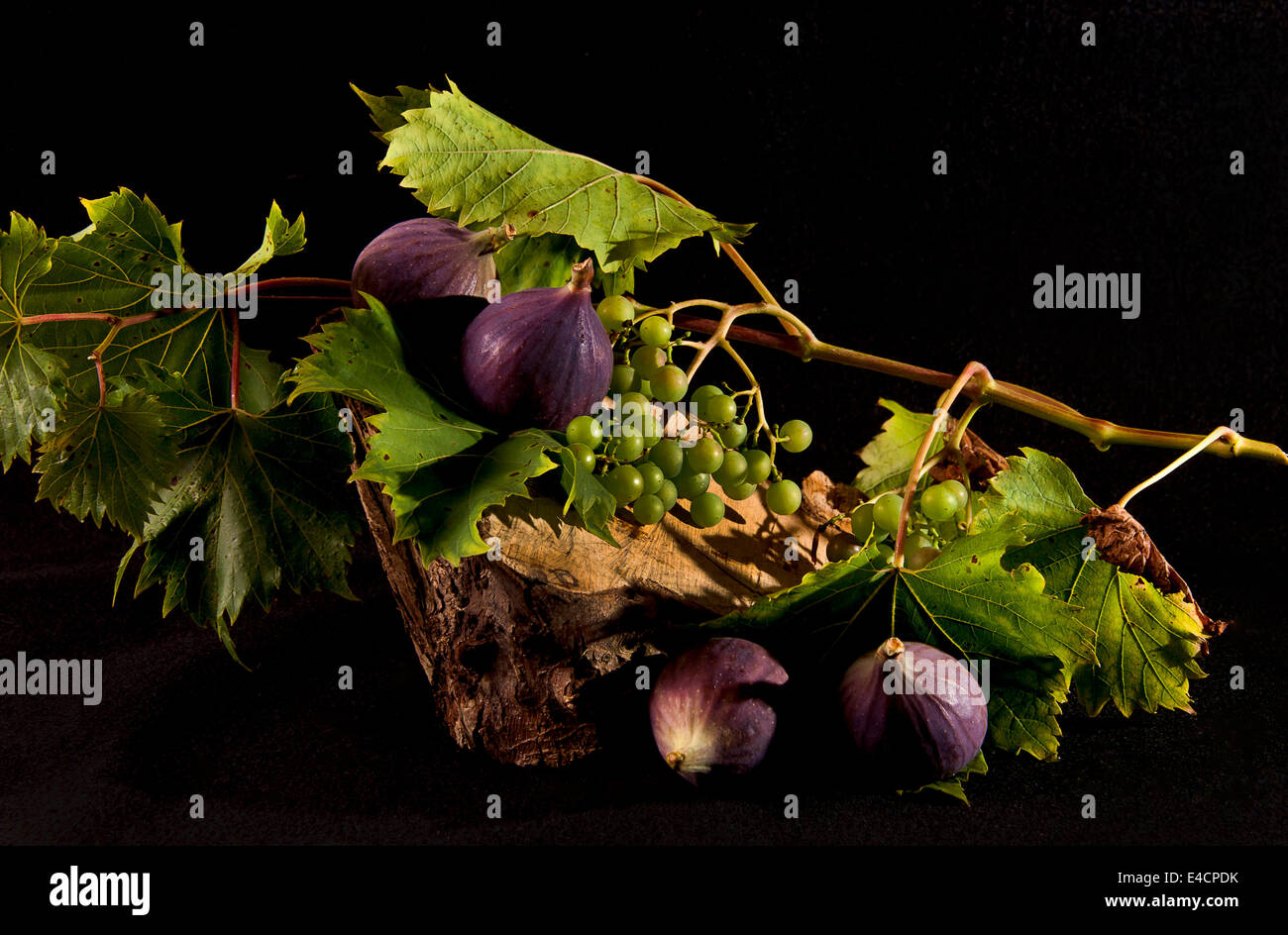 Still life of grape vine and figs on a log Stock Photo - Alamy