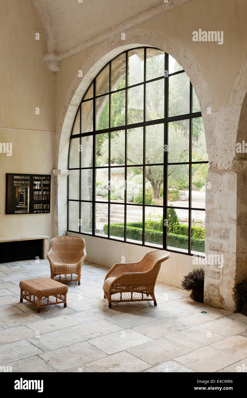 Stone floored gallery style space with large arched window and wicker ...