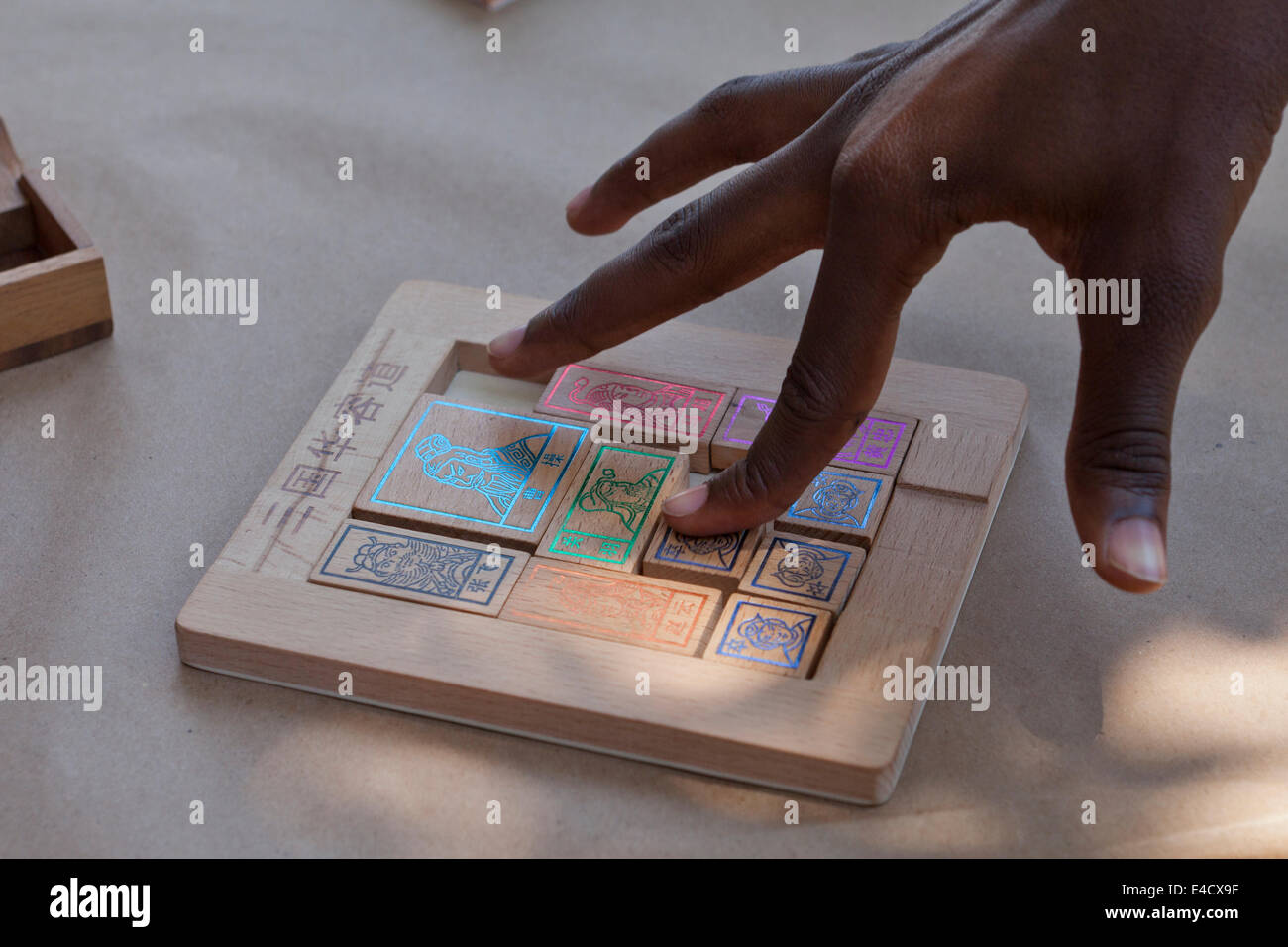 Woman moving piece on Chinese sliding block puzzle game (Huarong dao ...