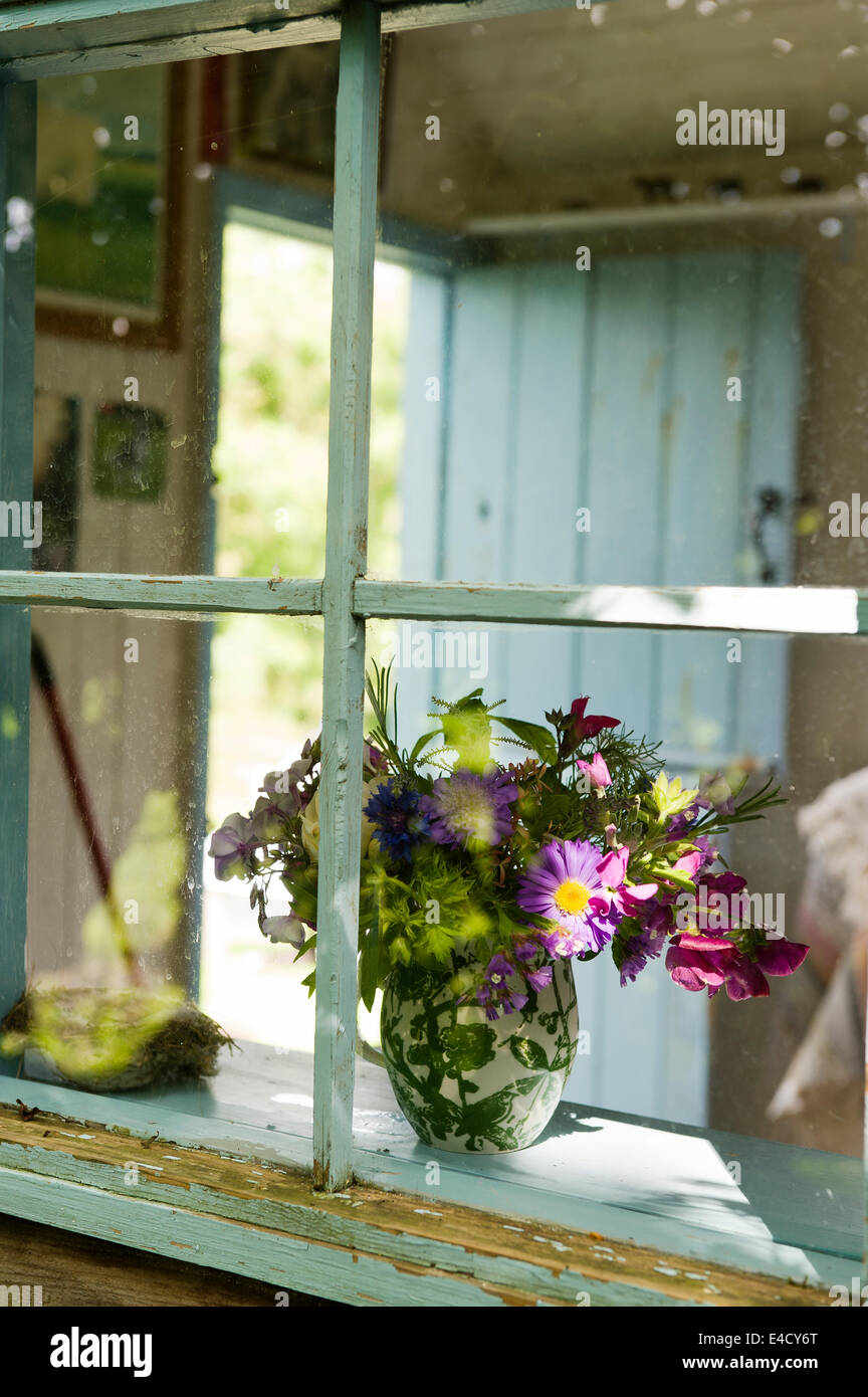 Distressed window with vase of sweet pea flowers seen on the inside ...