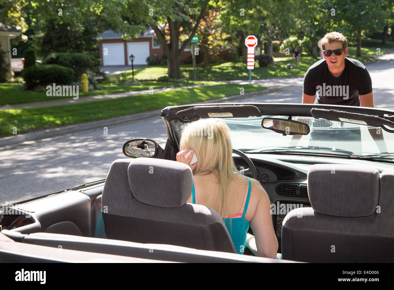 Focus on young woman making a cell phone call for help while a young ...
