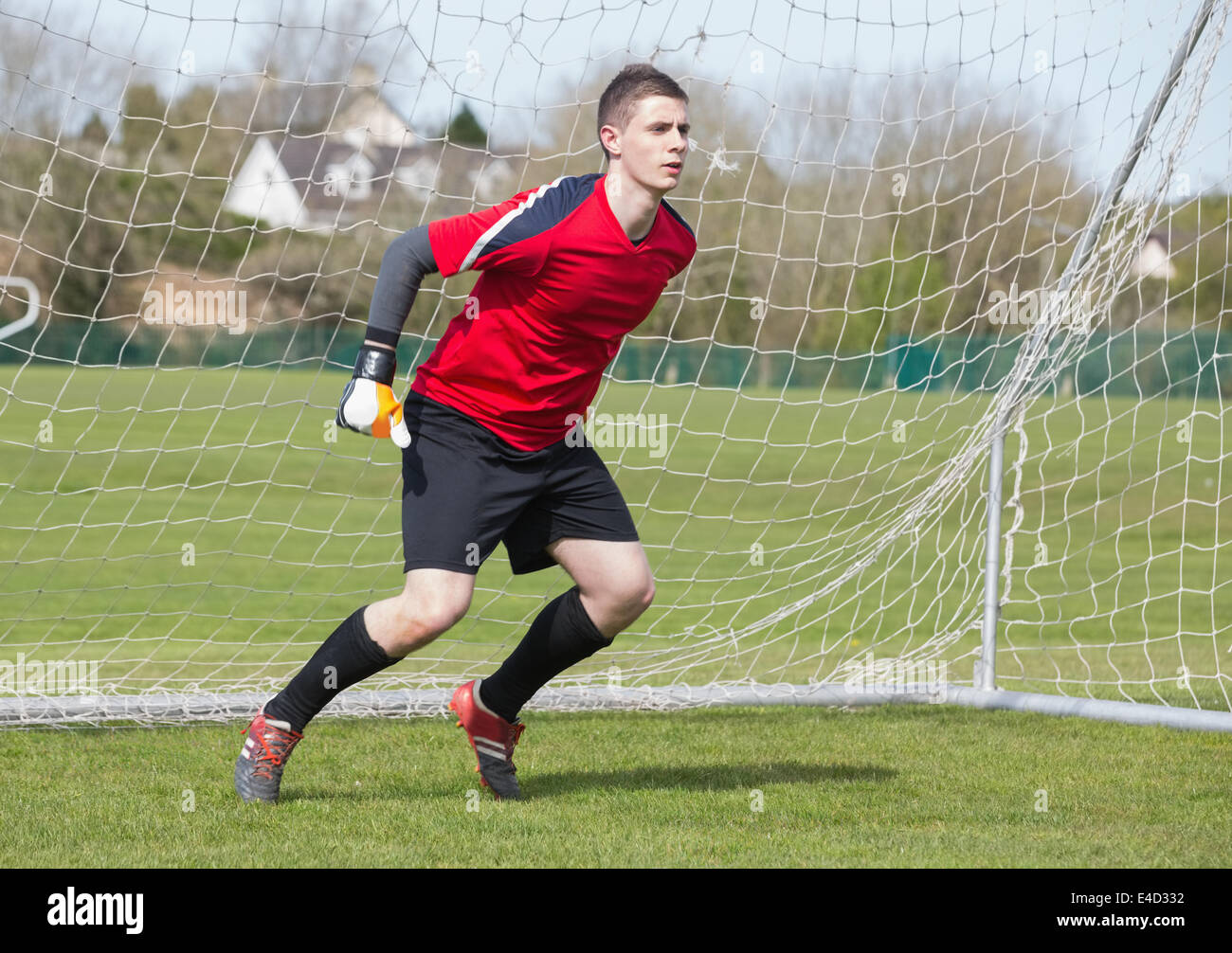 Goalkeeper in red ready to make a save Stock Photo - Alamy