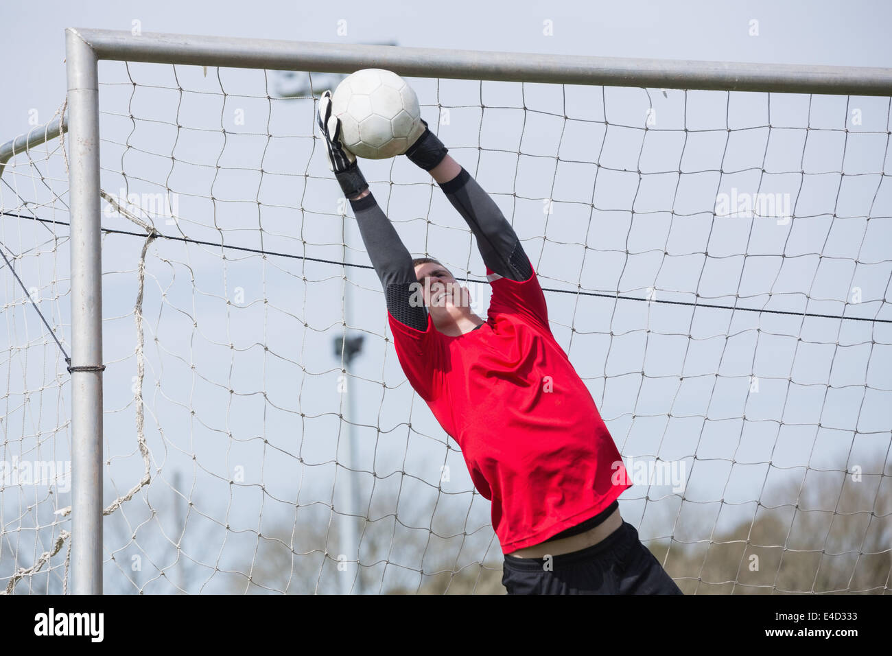 Goalkeeper in red jumping up to save a goal Stock Photo - Alamy