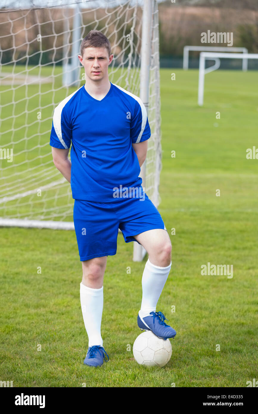 Football player in blue posing with the ball on pitch Stock Photo - Alamy