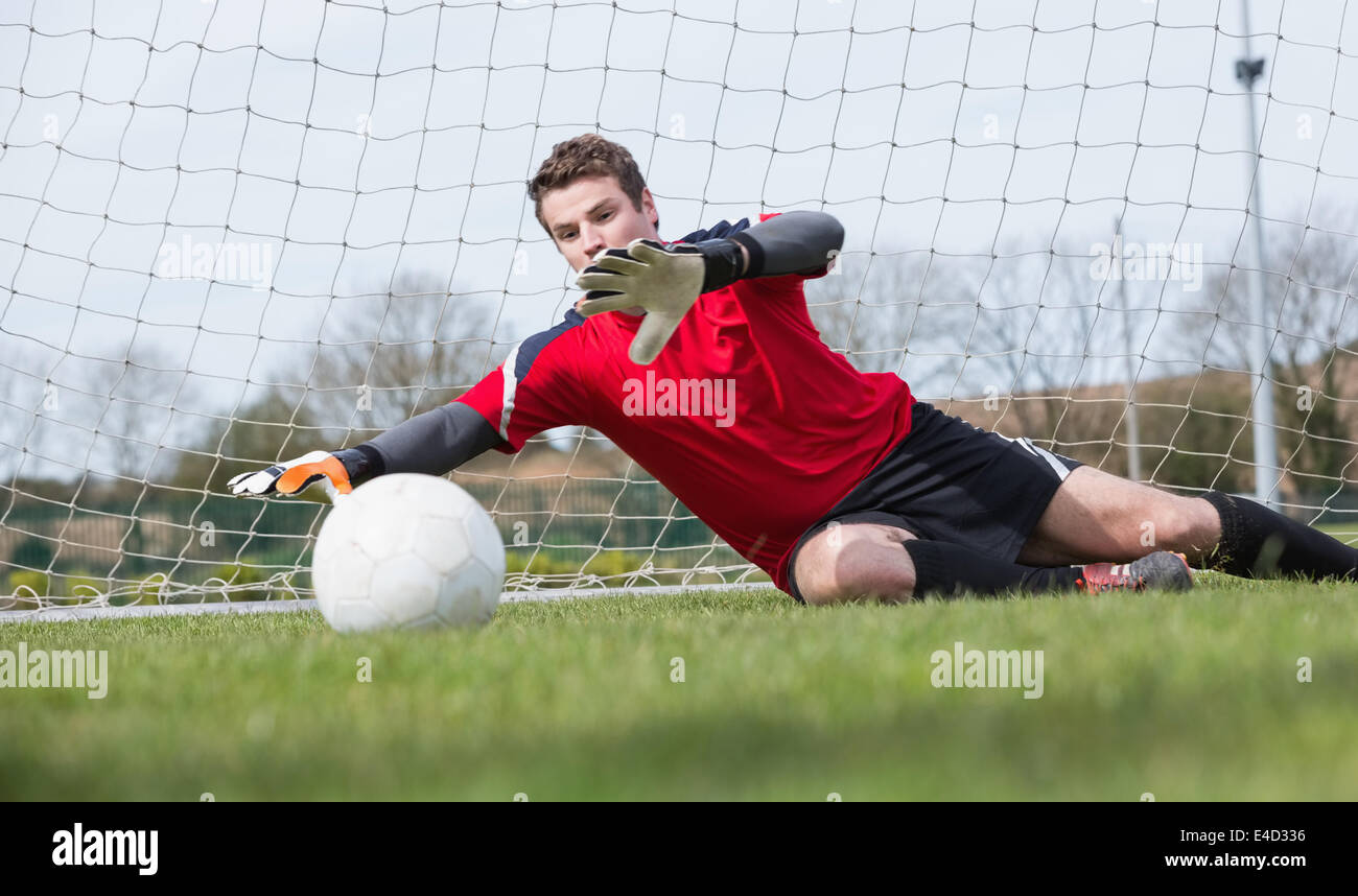 Goalkeeper in red saving a goal during a game Stock Photo - Alamy
