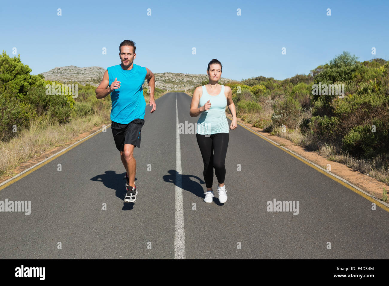Fit couple jogging on the open road together Stock Photo - Alamy