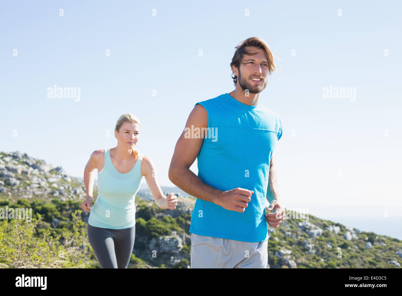 Fit couple jogging through countryside Stock Photo - Alamy