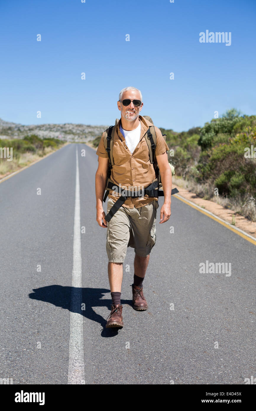 Handsome hiker walking on road and smiling at camera Stock Photo - Alamy