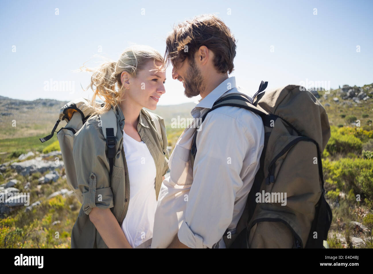 Hiking couple standing on mountain terrain smiling at each other Stock ...