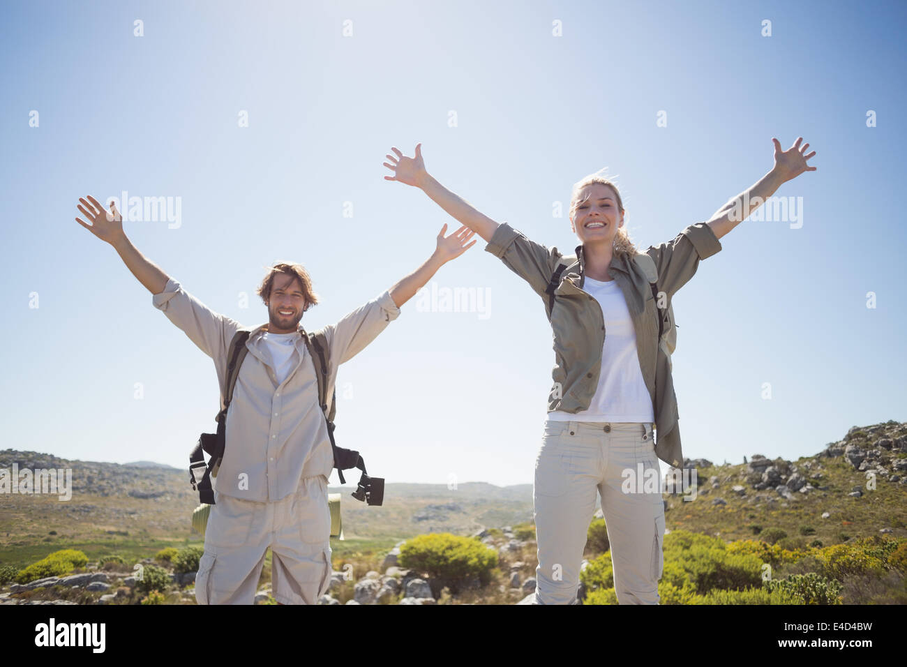 Hiking couple standing on mountain terrain smiling at camera Stock ...