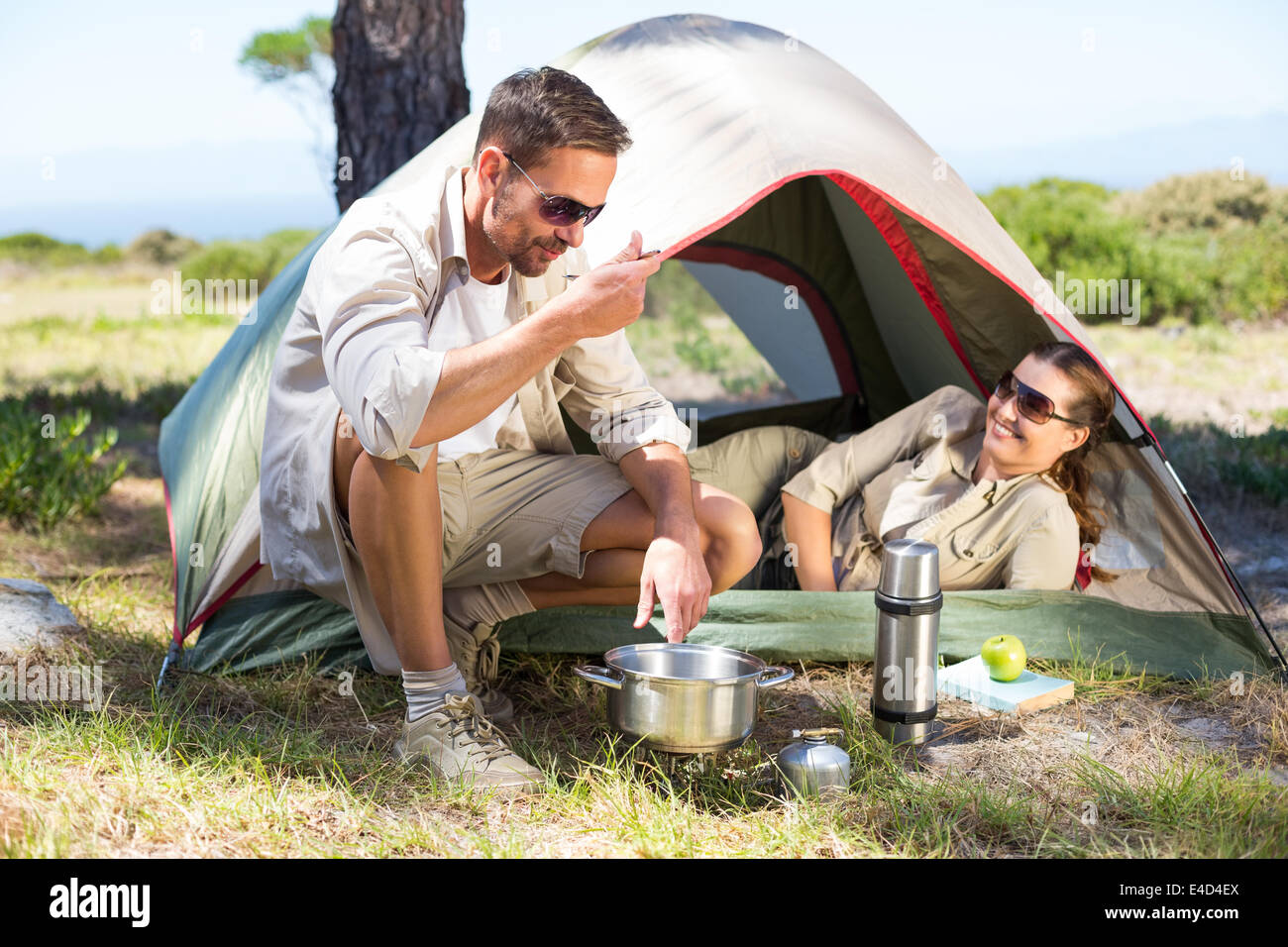 Outdoorsy couple cooking on camping stove outside tent Stock Photo - Alamy