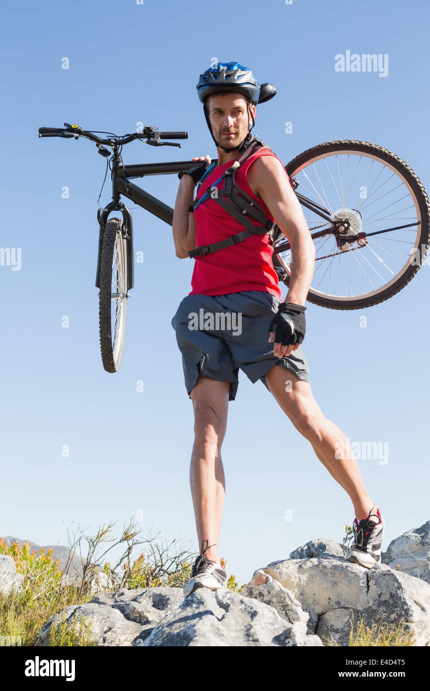 Fit cyclist carrying his bike on rocky terrain Stock Photo - Alamy