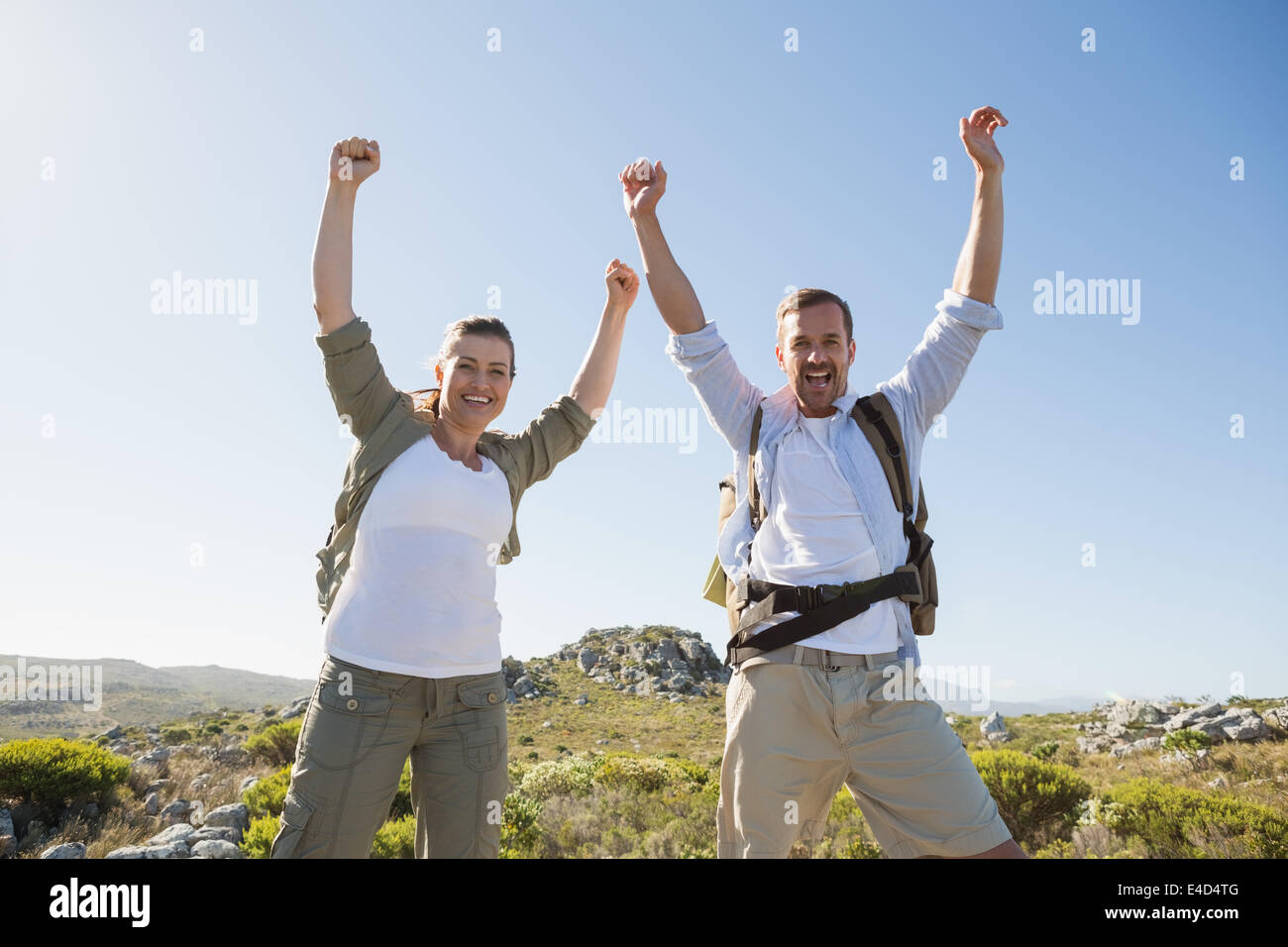 Hiking couple cheering at camera on mountain terrain Stock Photo - Alamy