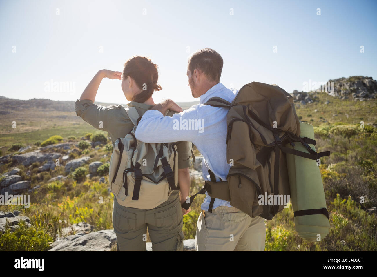 Hiking couple looking out over country terrain Stock Photo - Alamy