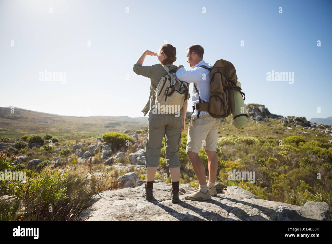 Hiking couple looking out over country terrain Stock Photo - Alamy