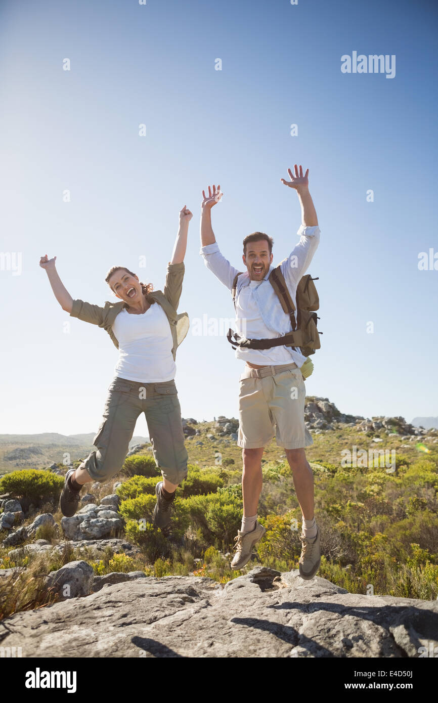 Hiking couple jumping and cheering on rocky terrain Stock Photo - Alamy