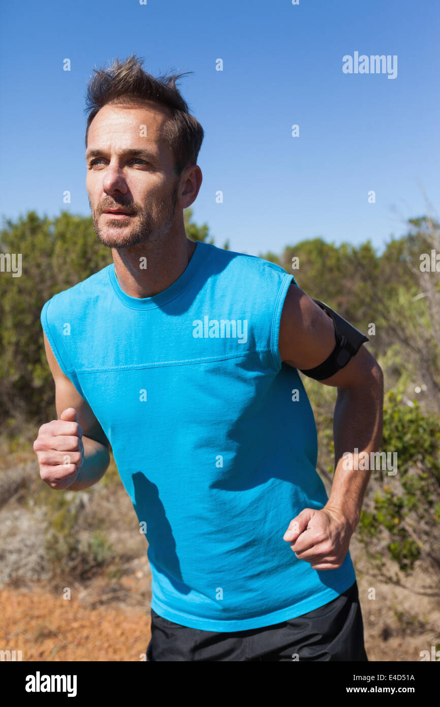 Athletic man jogging up country trail Stock Photo - Alamy