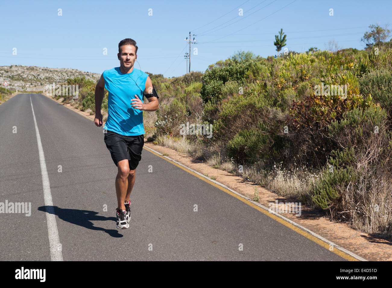 Athletic man jogging on open road Stock Photo - Alamy