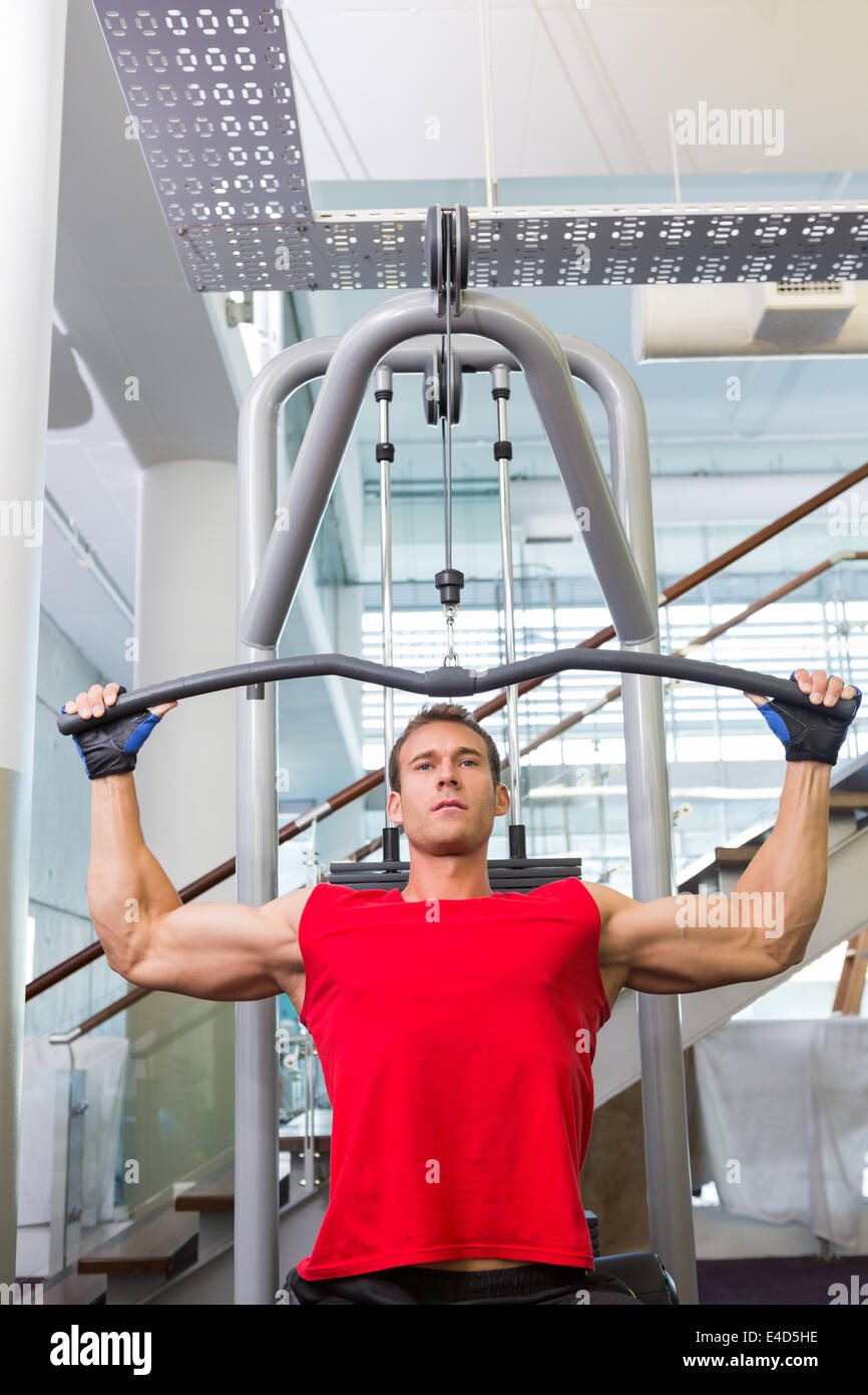 Strong man using weights machine for arms Stock Photo - Alamy