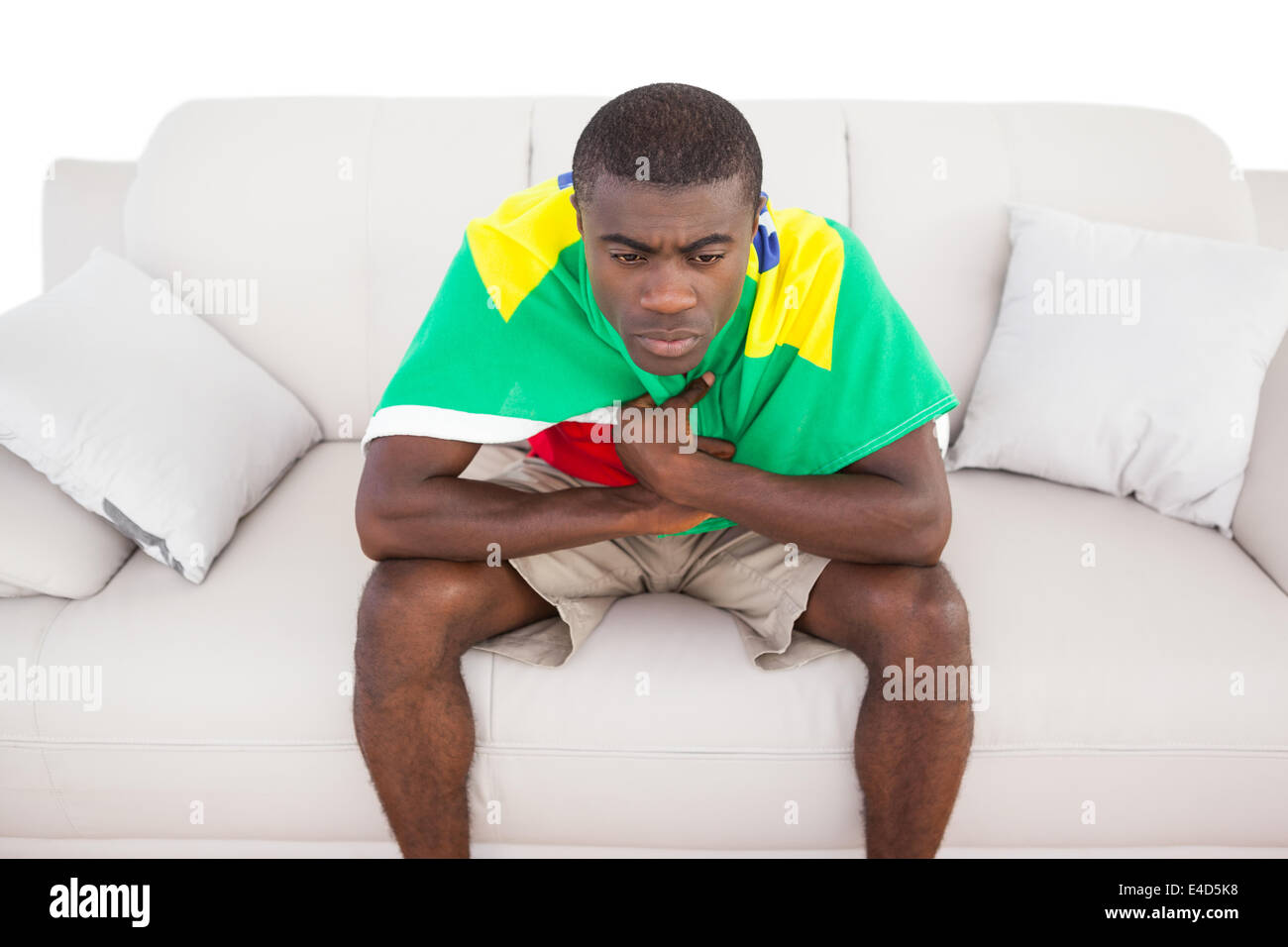 Upset brazilian football fan sitting on couch Stock Photo - Alamy