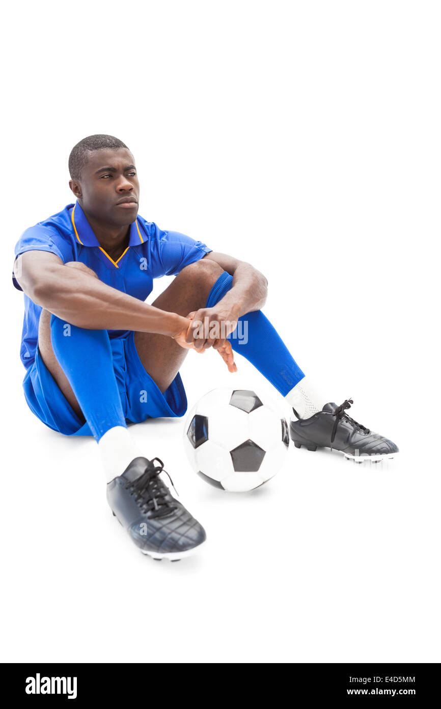 Football player sitting on the ground holding ball Stock Photo - Alamy