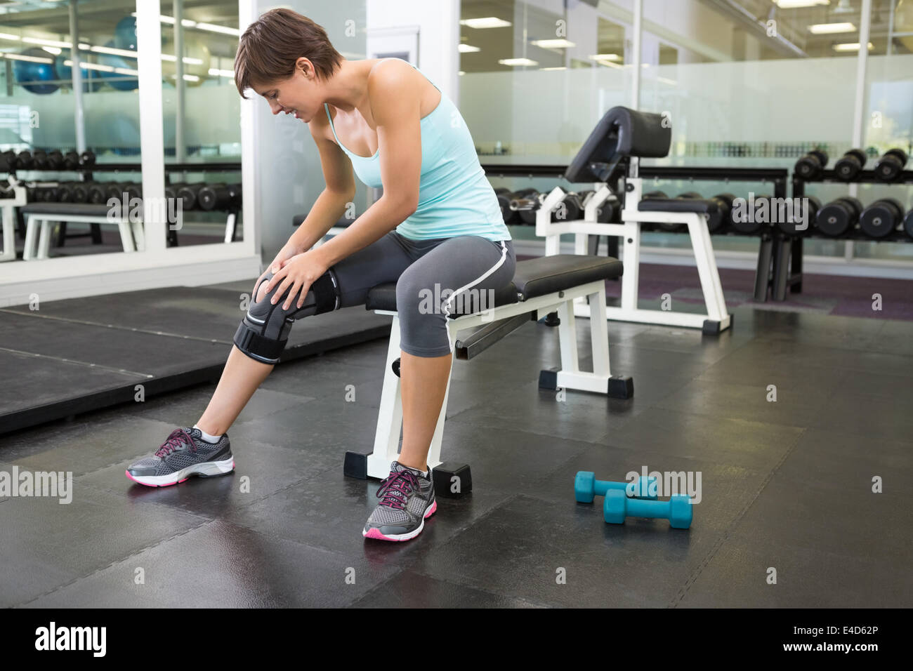 Fit brunette sitting on bench holding injured knee Stock Photo - Alamy