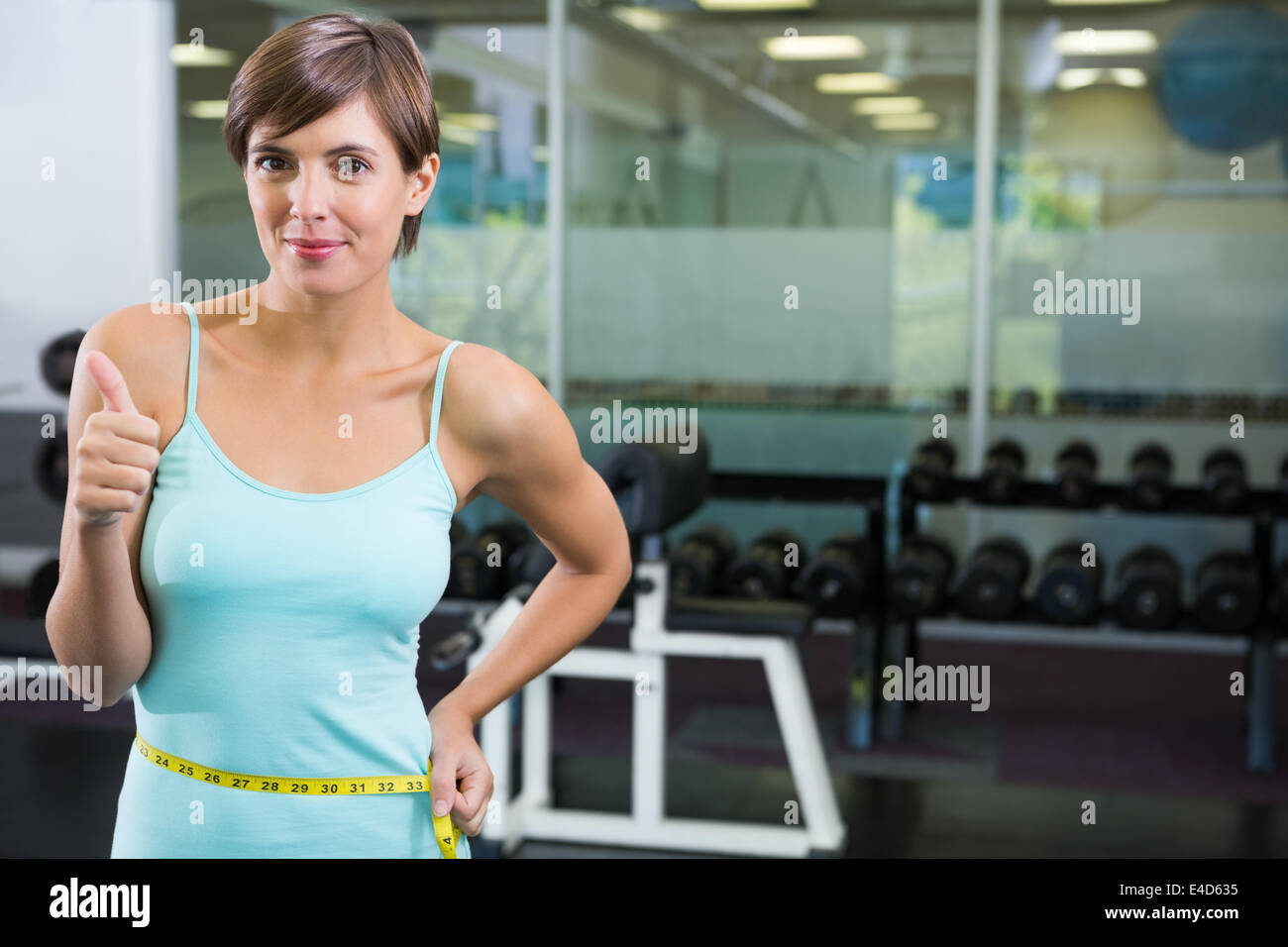 Fit brunette smiling at camera with measuring tape around waist Stock ...