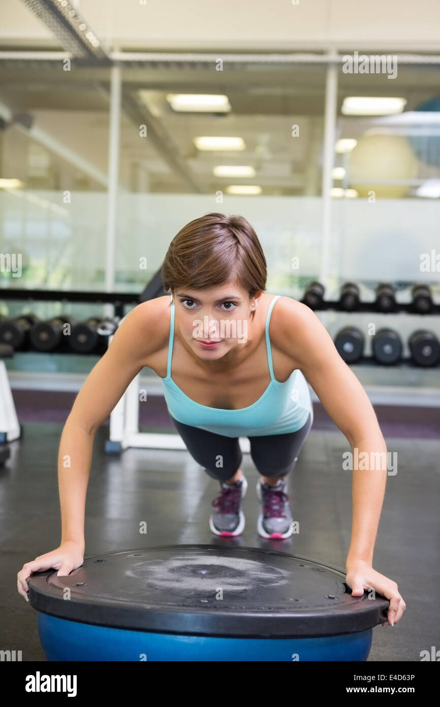 Fit brunette using bosu ball in plank position Stock Photo - Alamy
